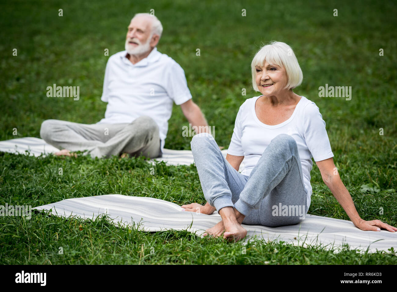 senior couple meditating in relaxation poses while sitting on yoga mats ...