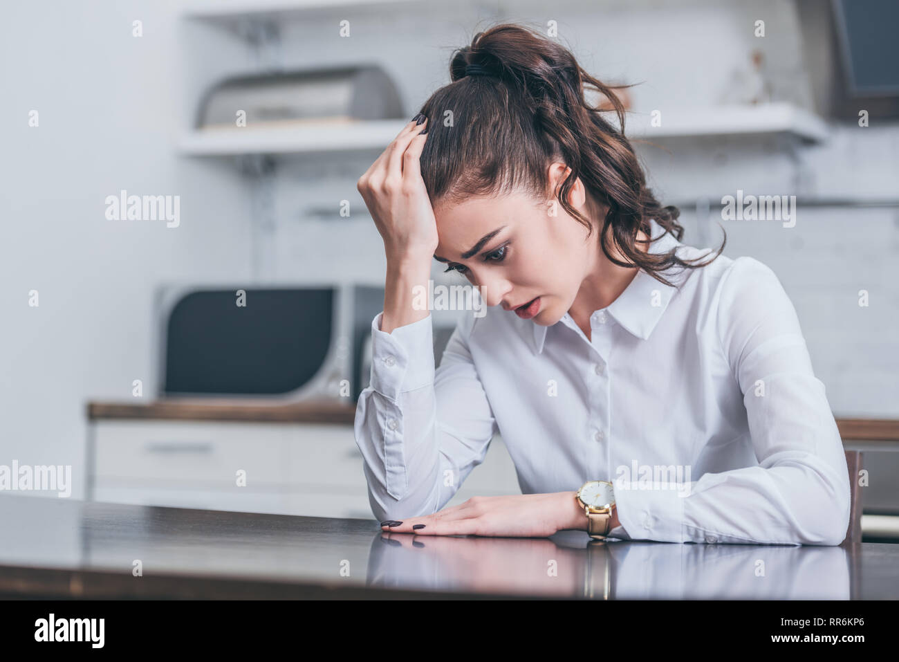 upset woman in white blouse sitting at table and crying in kitchen ...