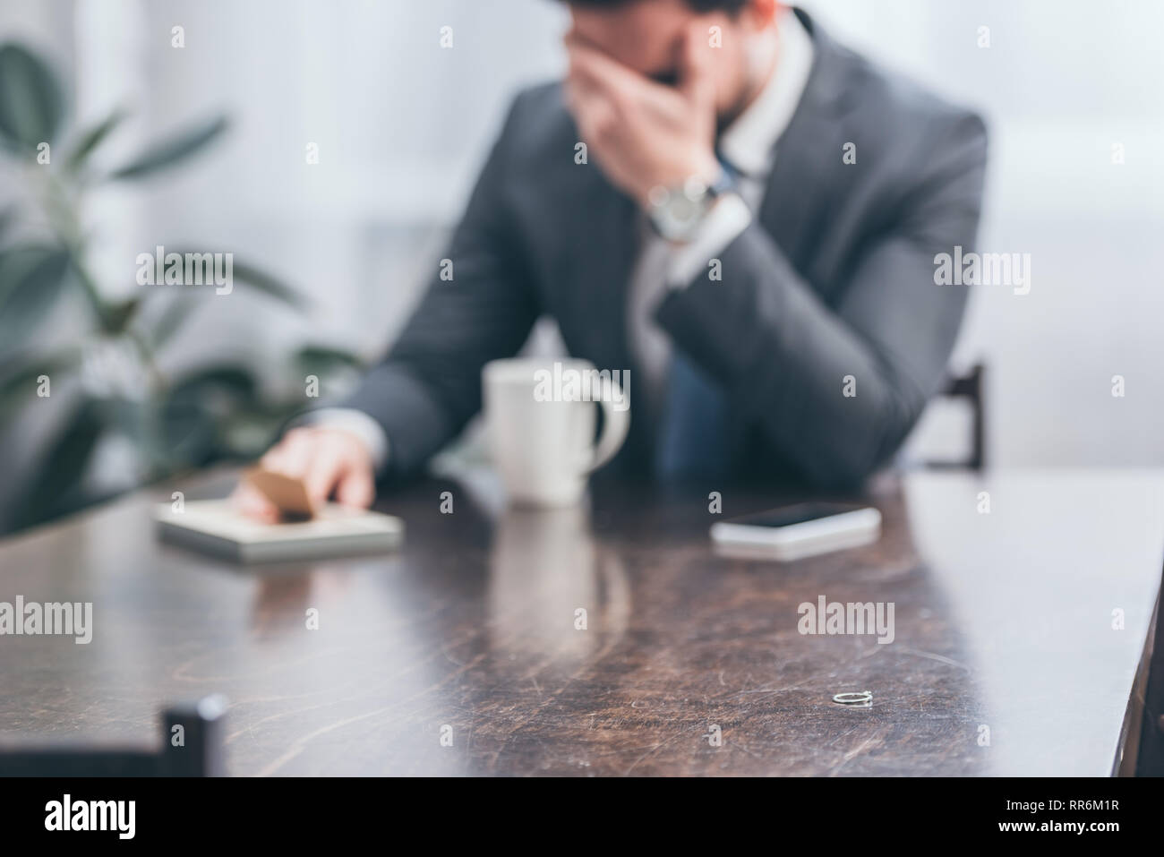 selective focus of ring at wooden table with crying man on background ...
