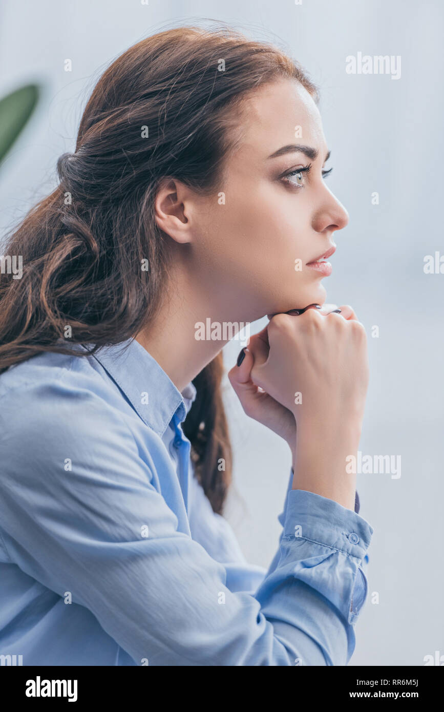 sad woman in blue blouse sitting and looking into distance at home ...