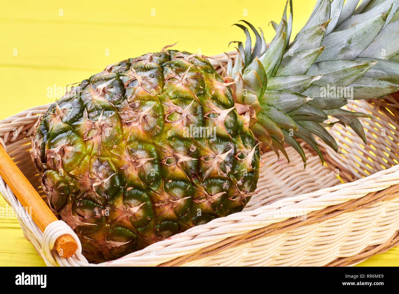 Big green pineapple in wicker basket Stock Photo - Alamy