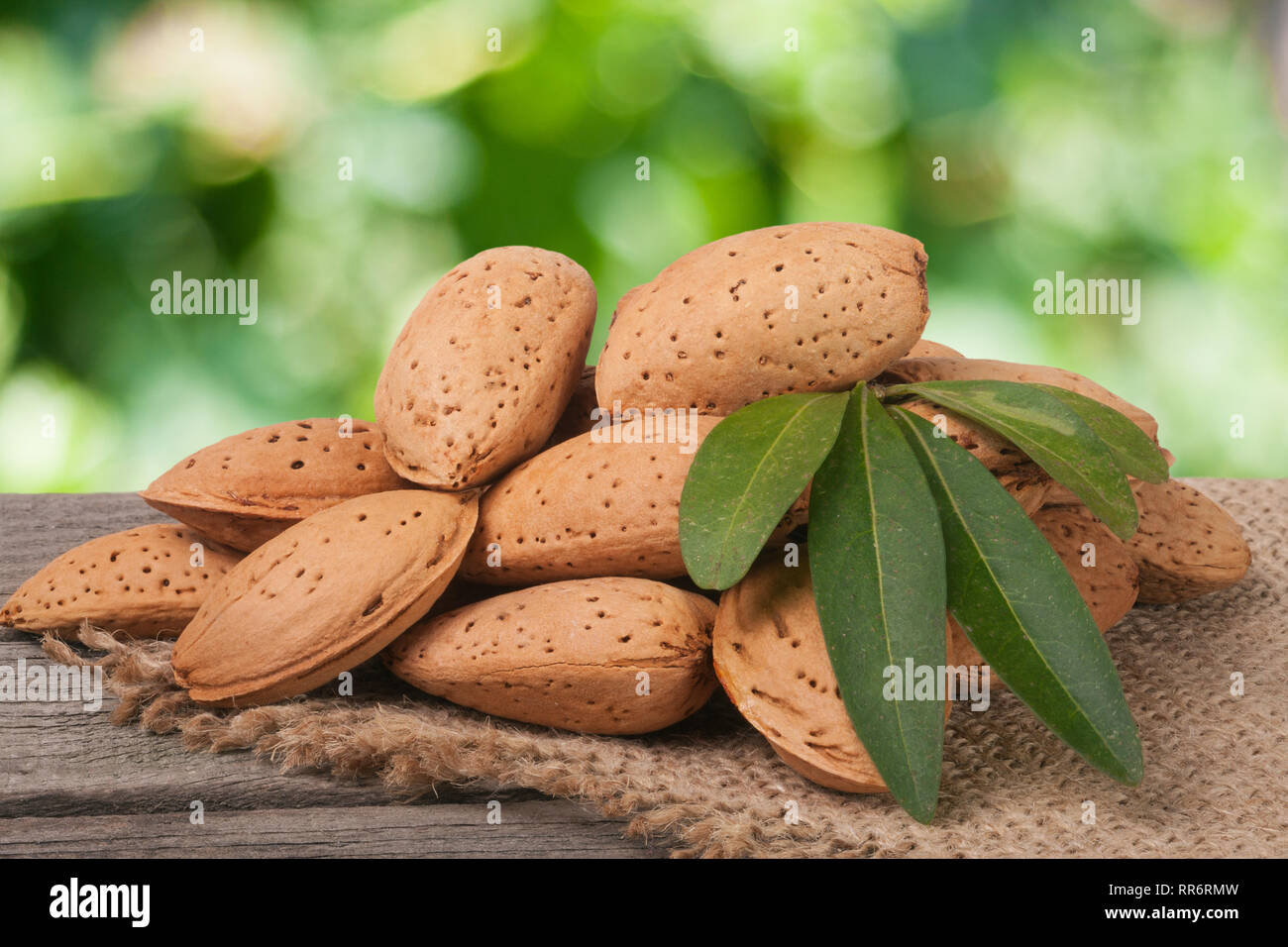 heap of almonds in their skins with leaf isolated on white background ...