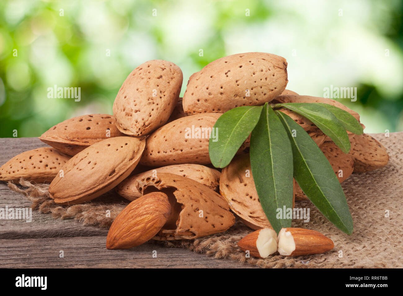heap of almonds in their skins with leaf isolated on white background ...