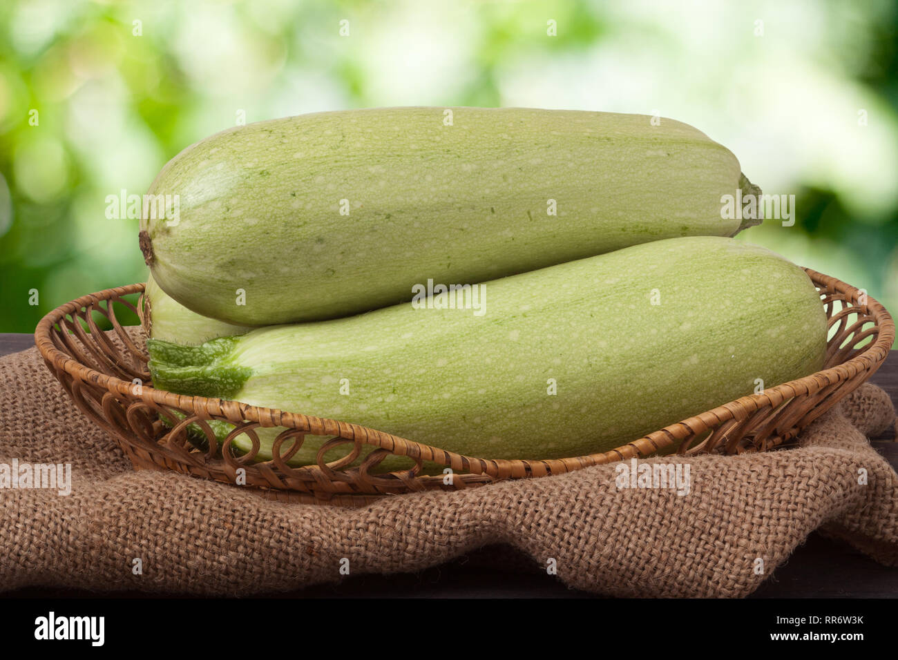 courgettes on the wooden table with sacking and a blurred background ...