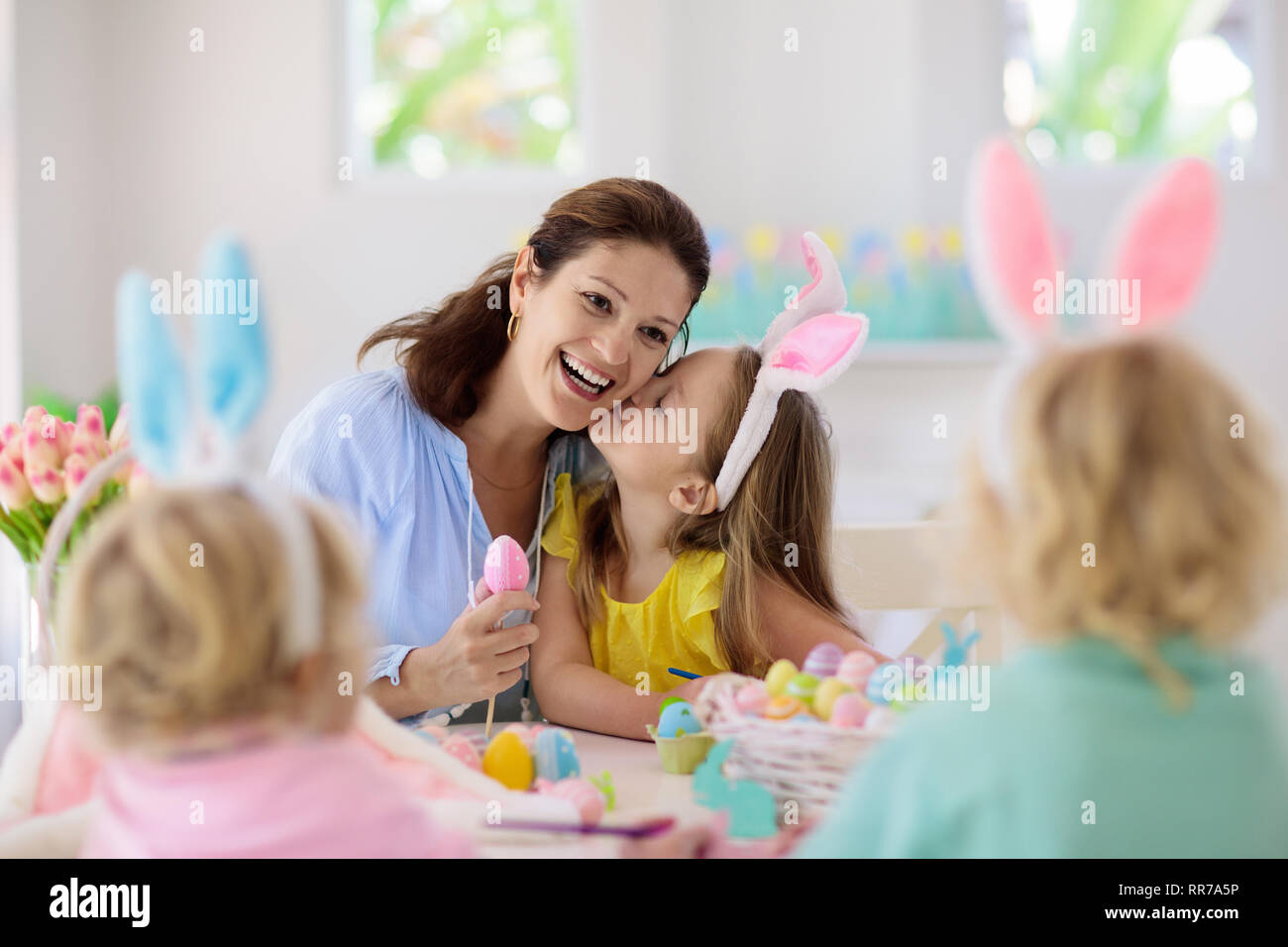 Mother and kids color Easter eggs. Mom, little girl and boy with bunny ...