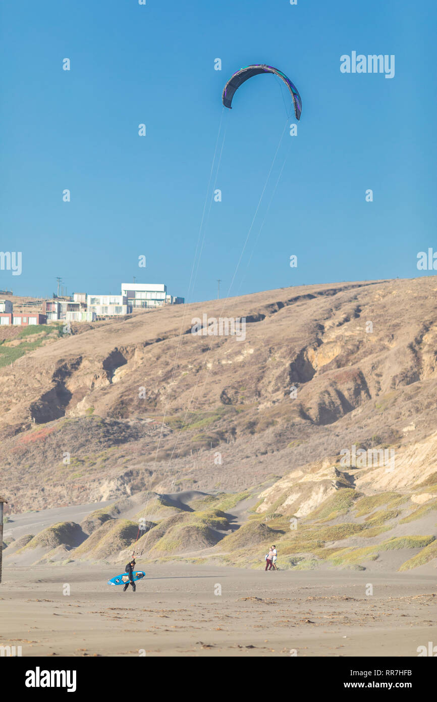 Kite surfer walking on the beach after practising kite surfing over the ...