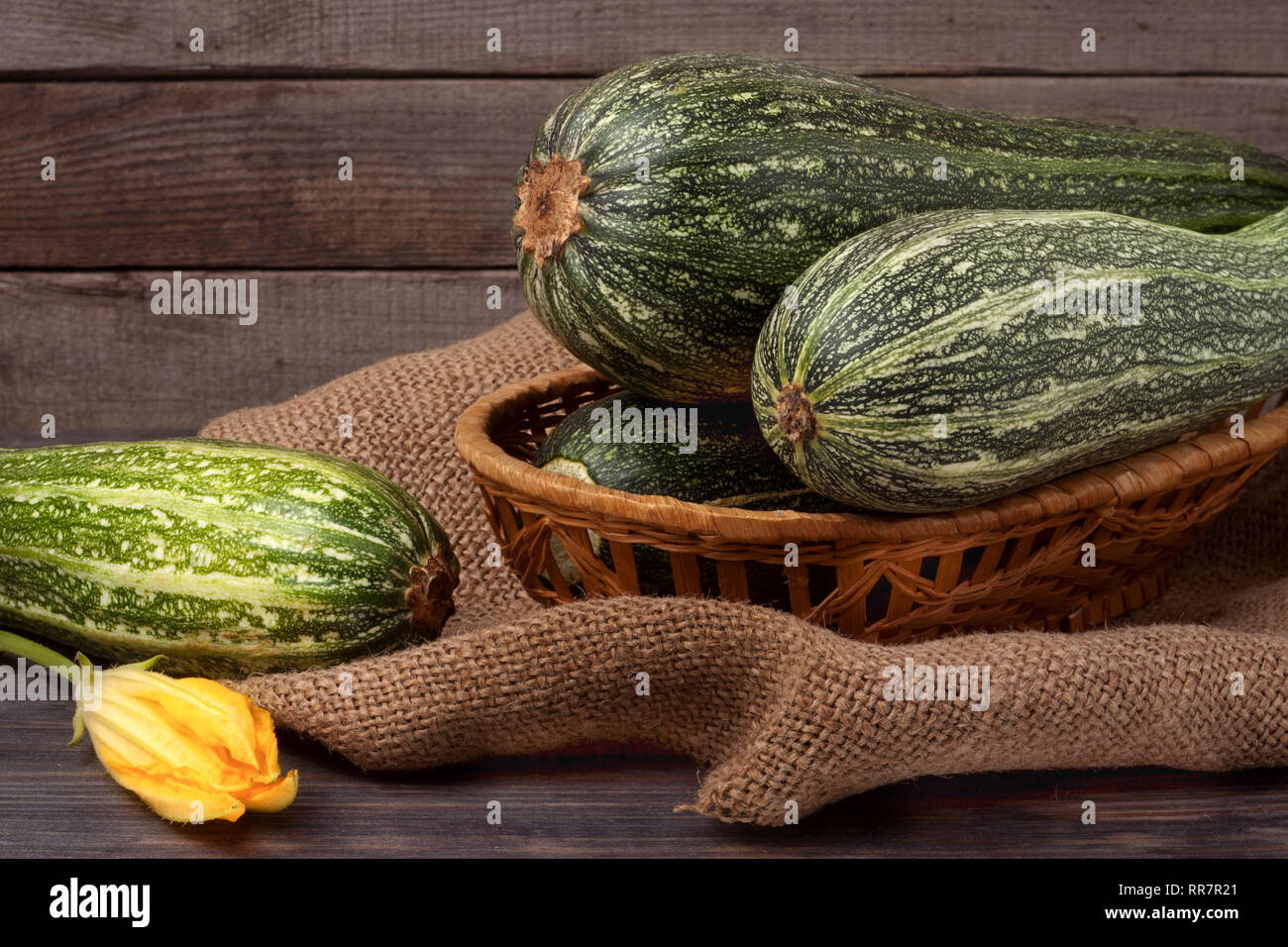 green zucchini or courgettes with a flower on sackcloth wooden ...