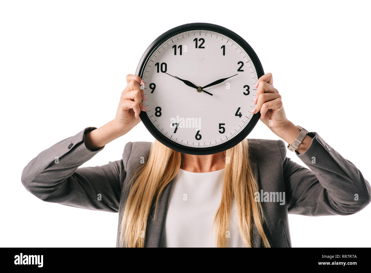 businesswoman holding clock in front of the face, isolated on white ...