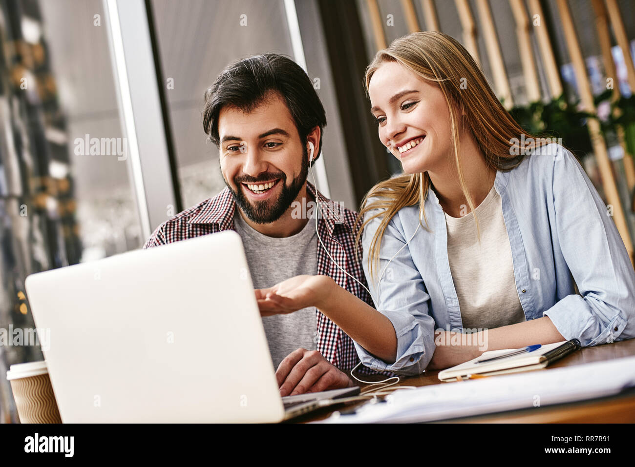 Man and woman looking on the screen with a smile while listening to ...