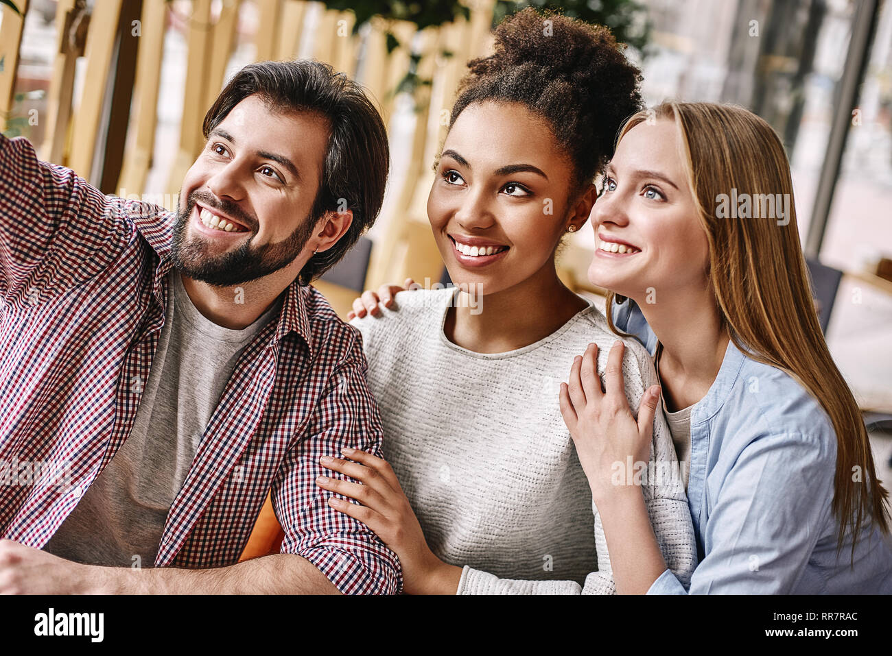 Three laughing young business people in casual wear smile to make shot ...