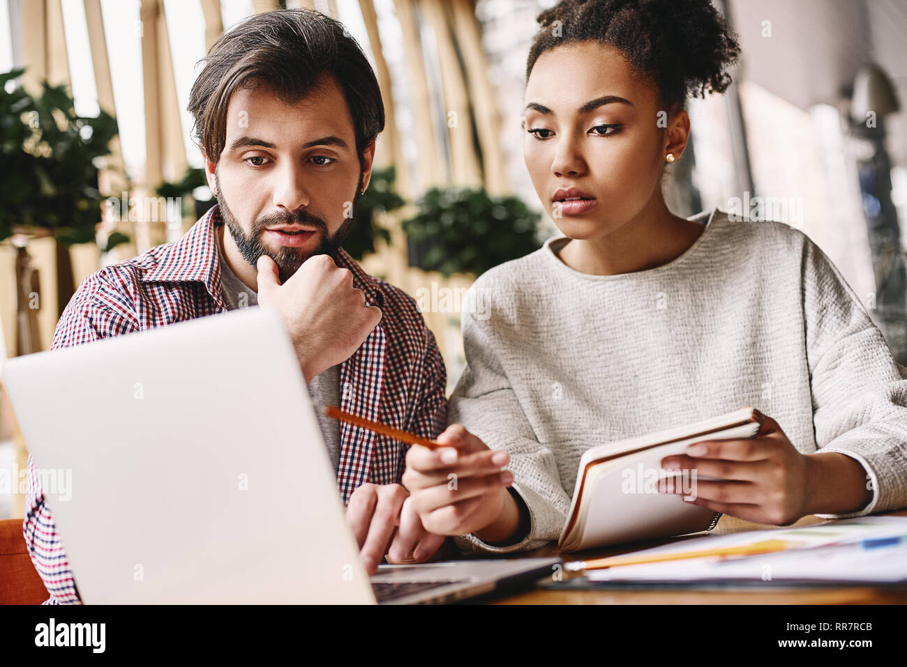 Two colleagues co-working while using laptop computer. Looking on the ...