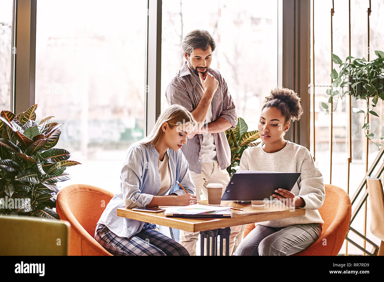 Group of young co-workers discussing ideas with each other in modern ...