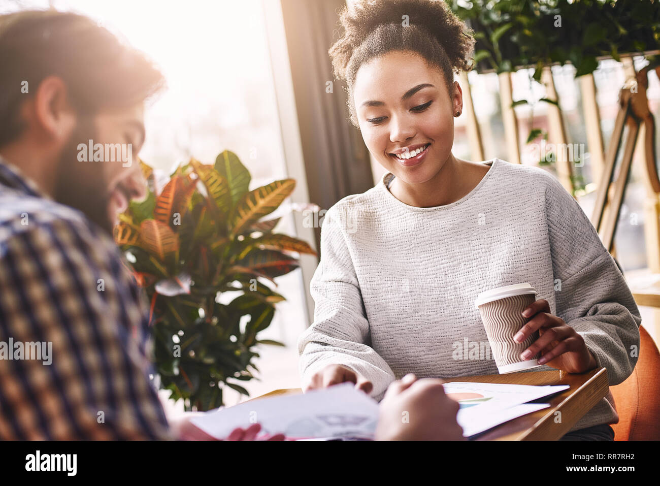 Two cheerful colleagues discussing new ideas sitting over coffee table ...