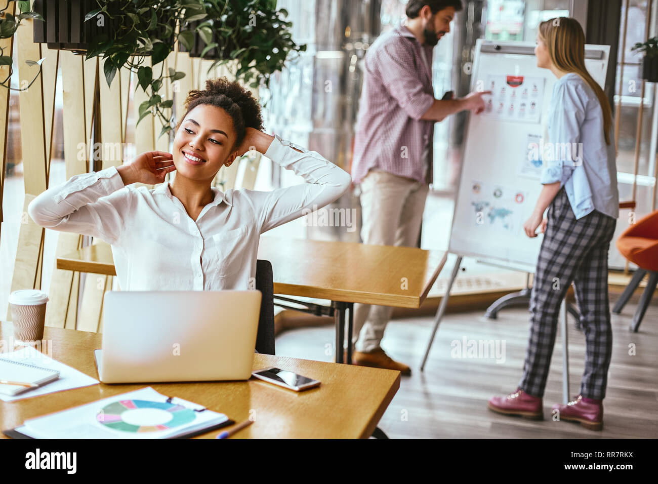 Beautiful young woman in white shirt using laptop computer, sitting at ...