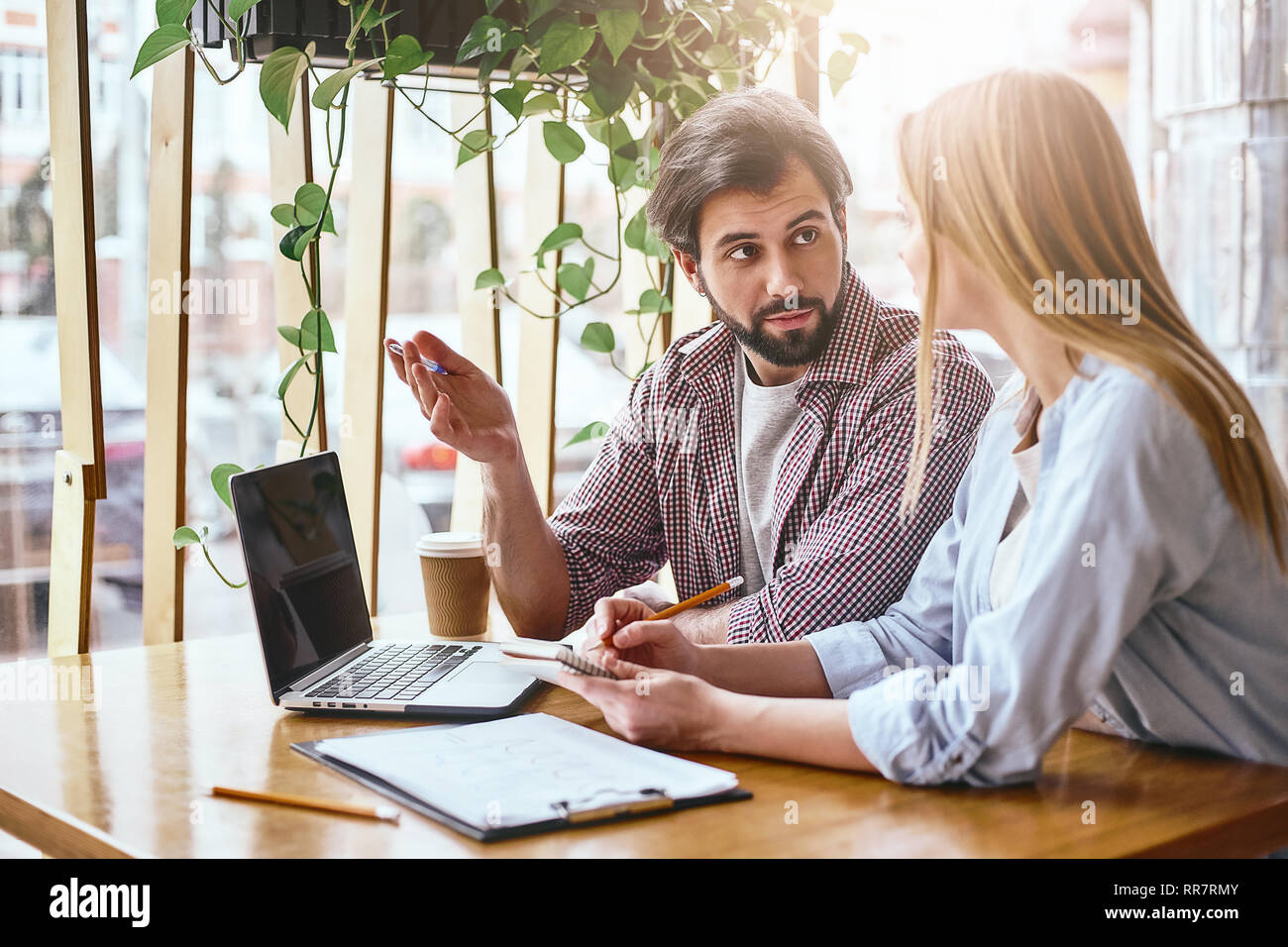 Two cheerful colleagues discussing new ideas in office . Bearded man ...