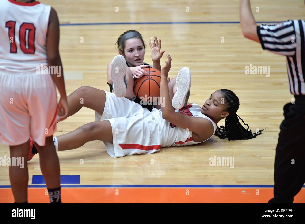 Opposing players battle for possession of the basketball on the floor ...