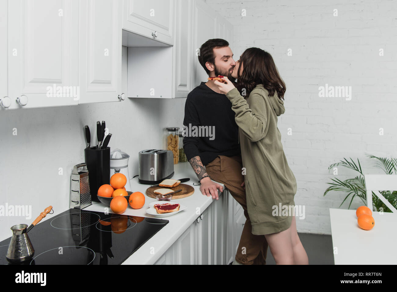 beautiful young romantic couple kissing during breakfast in kitchen ...