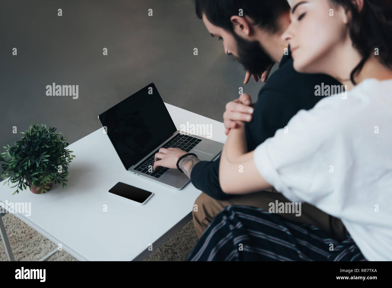 couple sitting ang hugging while using laptop with blank screen at home ...