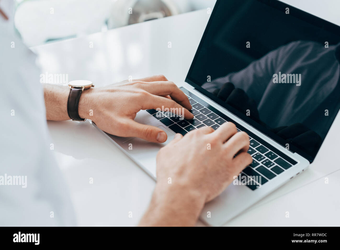 Partial view of man in wristwatch typing on laptop keyboard Stock Photo - Alamy