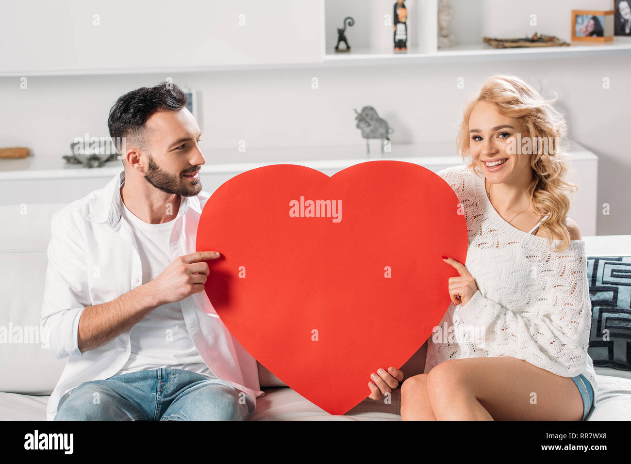 Smiling romantic couple holding big red heart Stock Photo - Alamy