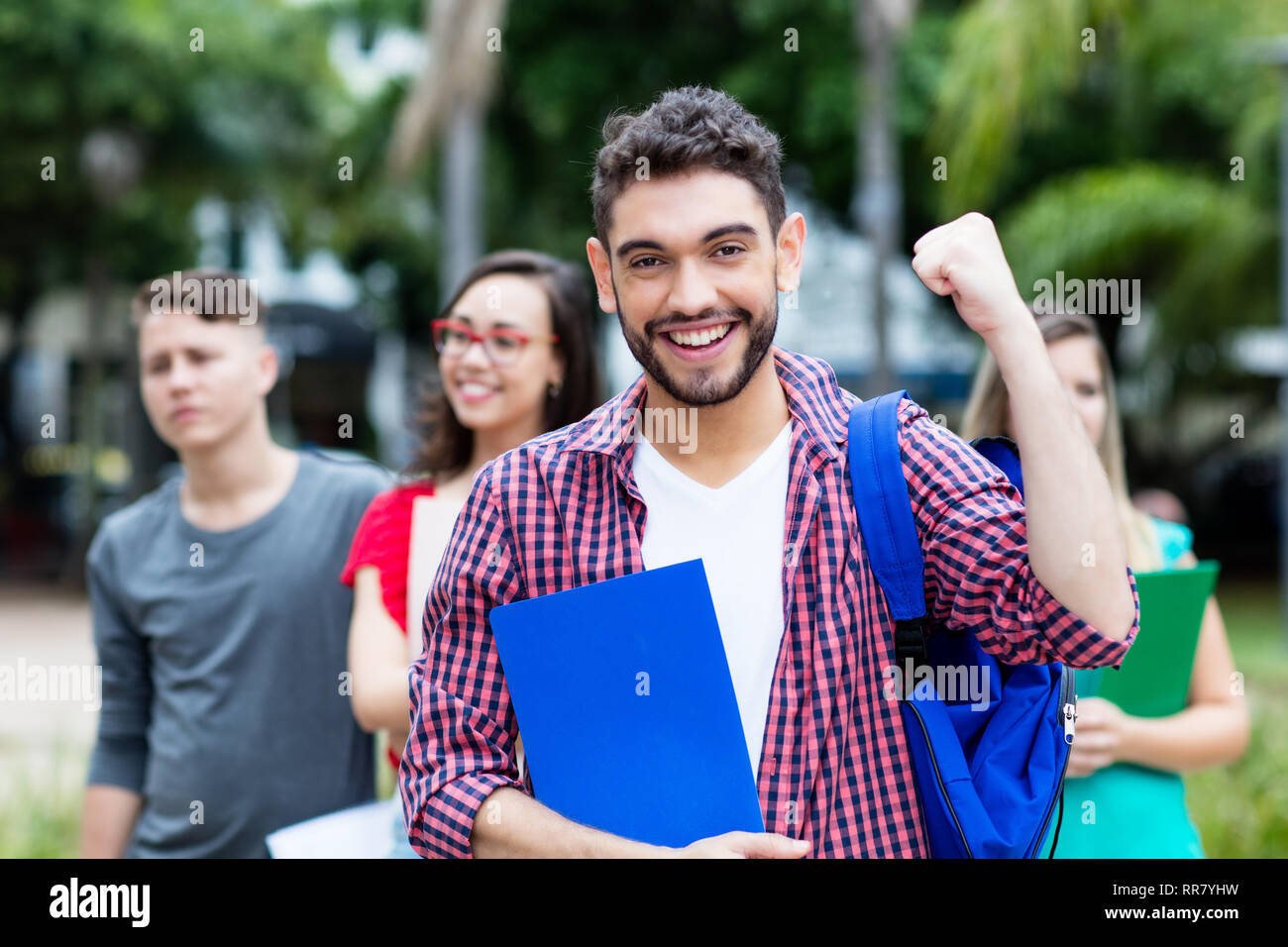 Successful spanish male student with group of other students outdoor in ...