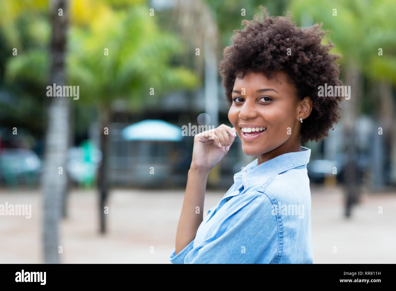 Laughing brazilian young adult woman outdoor in summer in the city ...