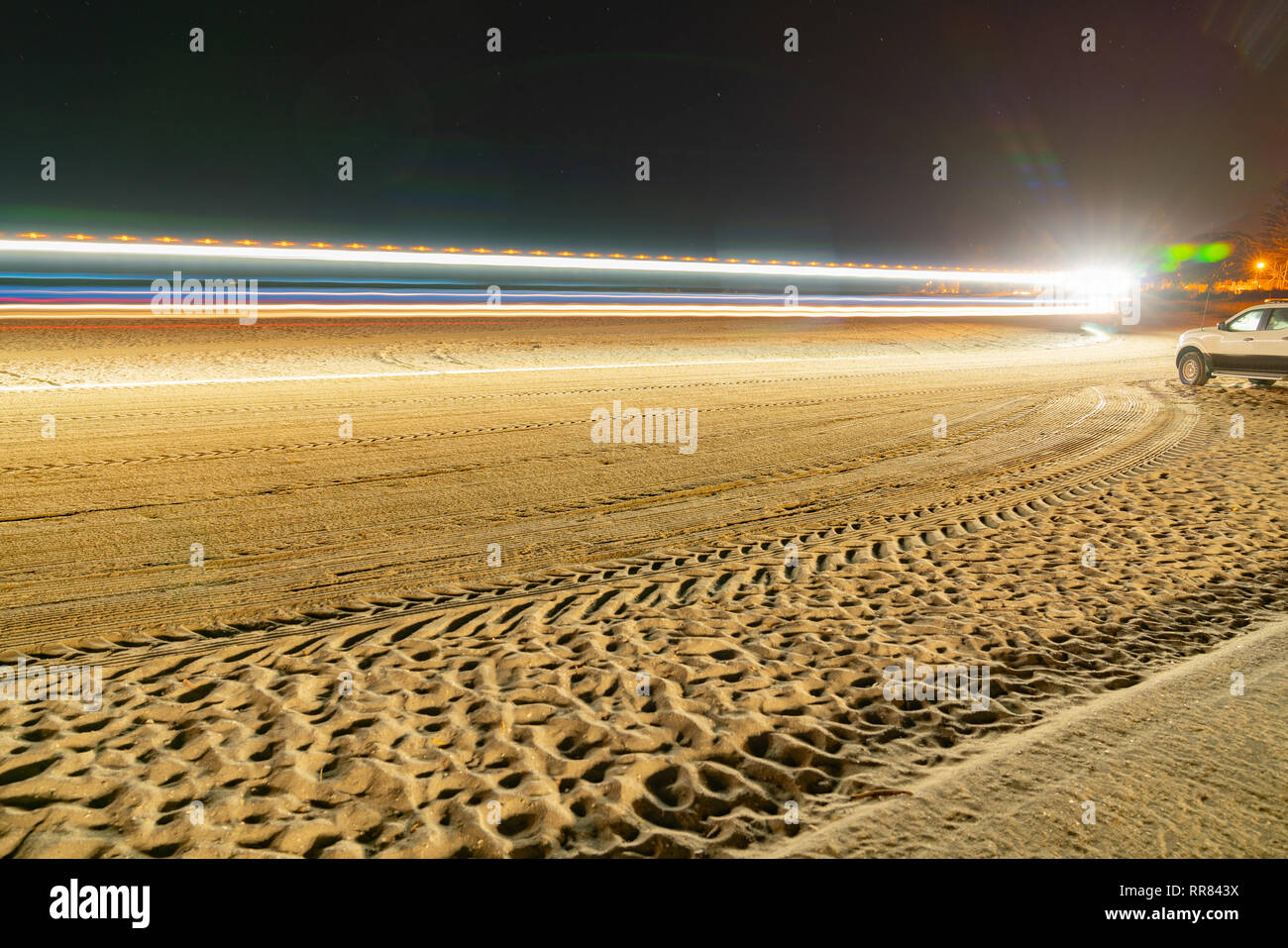 Beach sand groomer headlight light trails with tyre tread patterns in ...