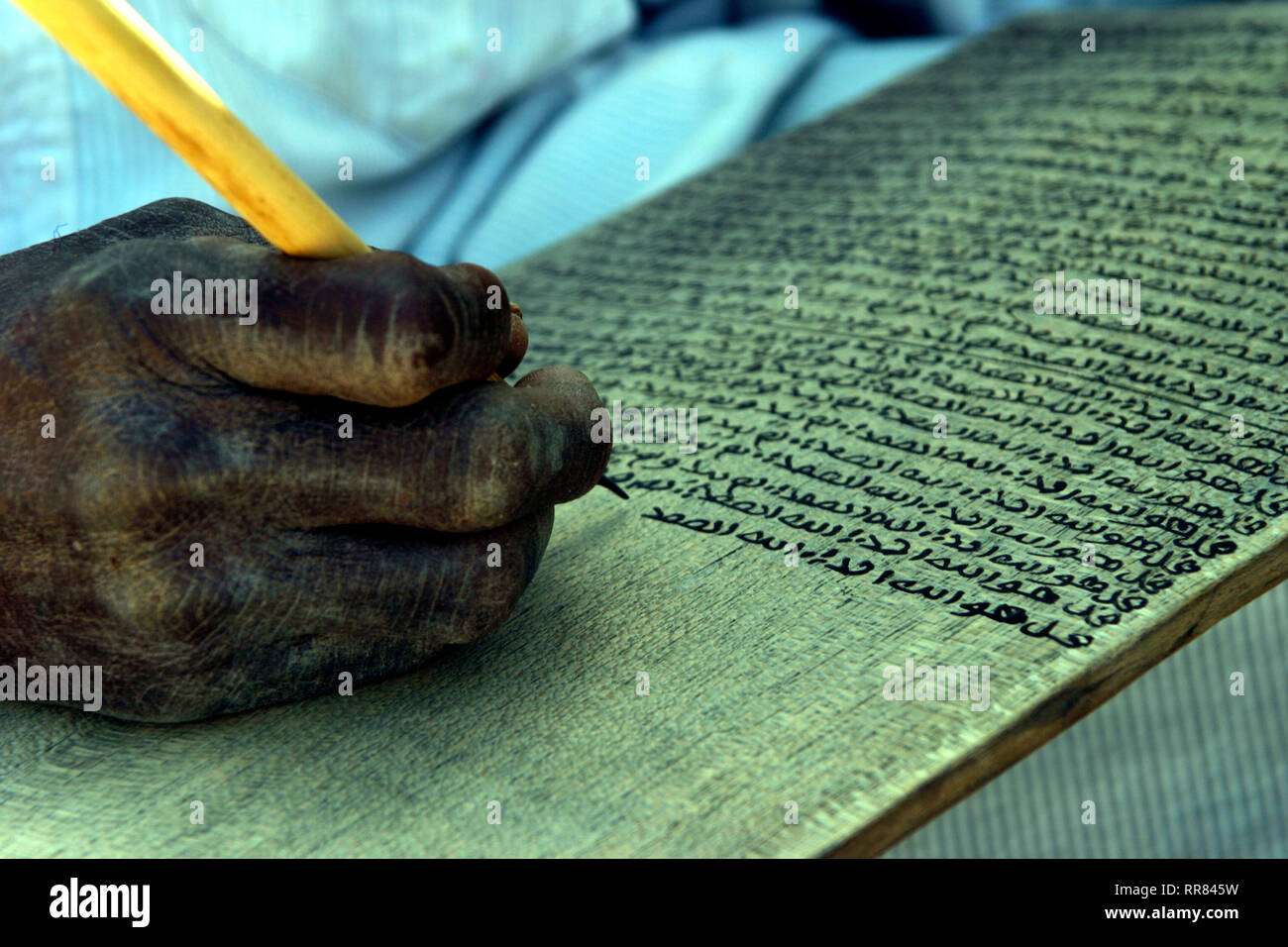 A black hand writing verses from the Holy Qur'an on a board in Chad ...