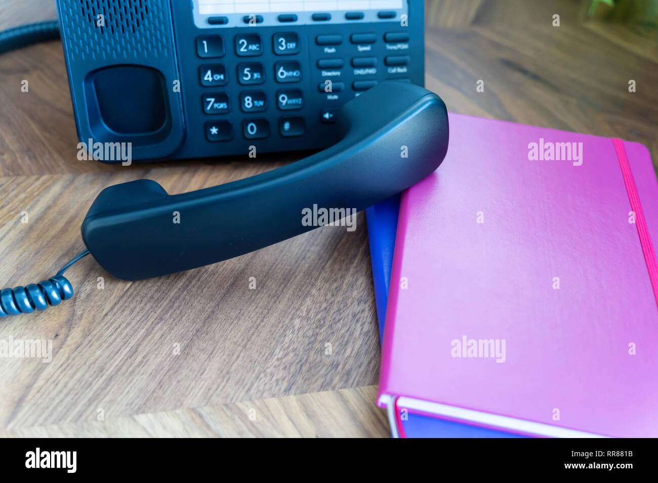 Office Telephone console on wood table with notebooks Stock Photo - Alamy
