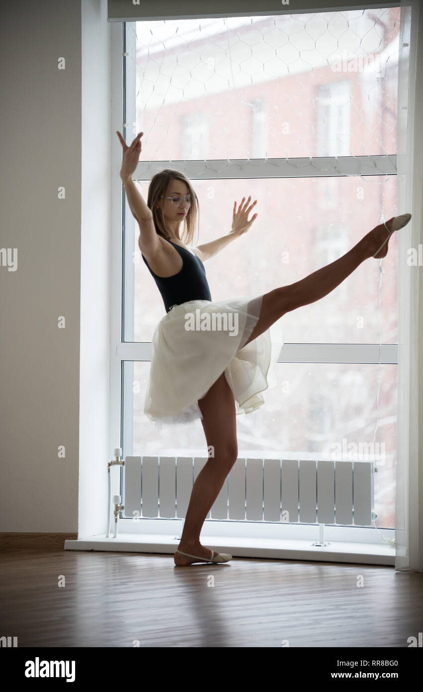 Girl ballerina standing with raised leg in the studio, telephoto shot ...
