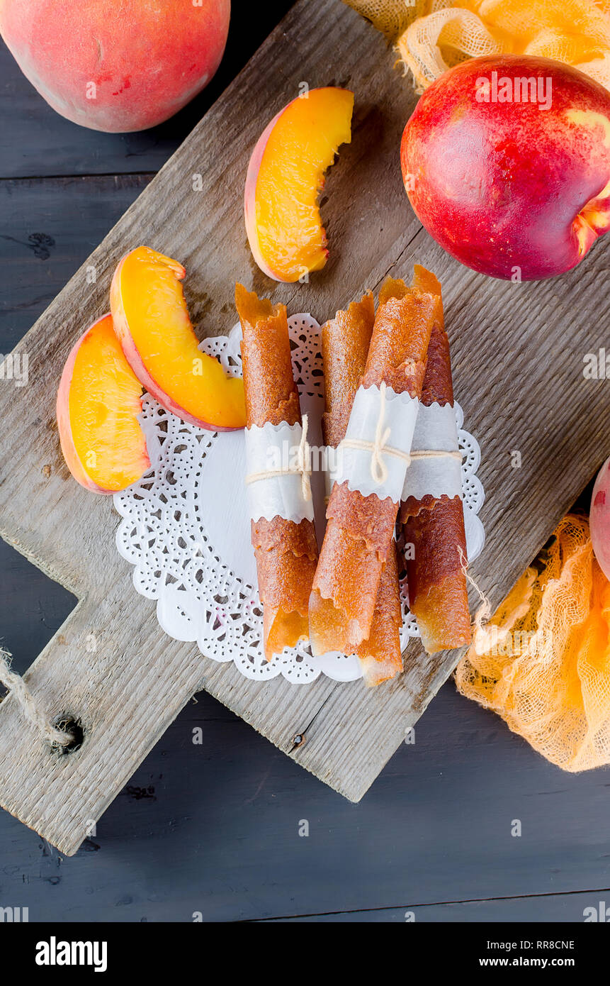 ripe fresh juicy peach, slice fruit and peach leather rolls on dark ...