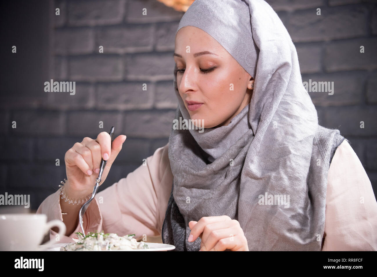 Muslim woman eats with a fork in a cafe, telephoto shot Stock Photo - Alamy