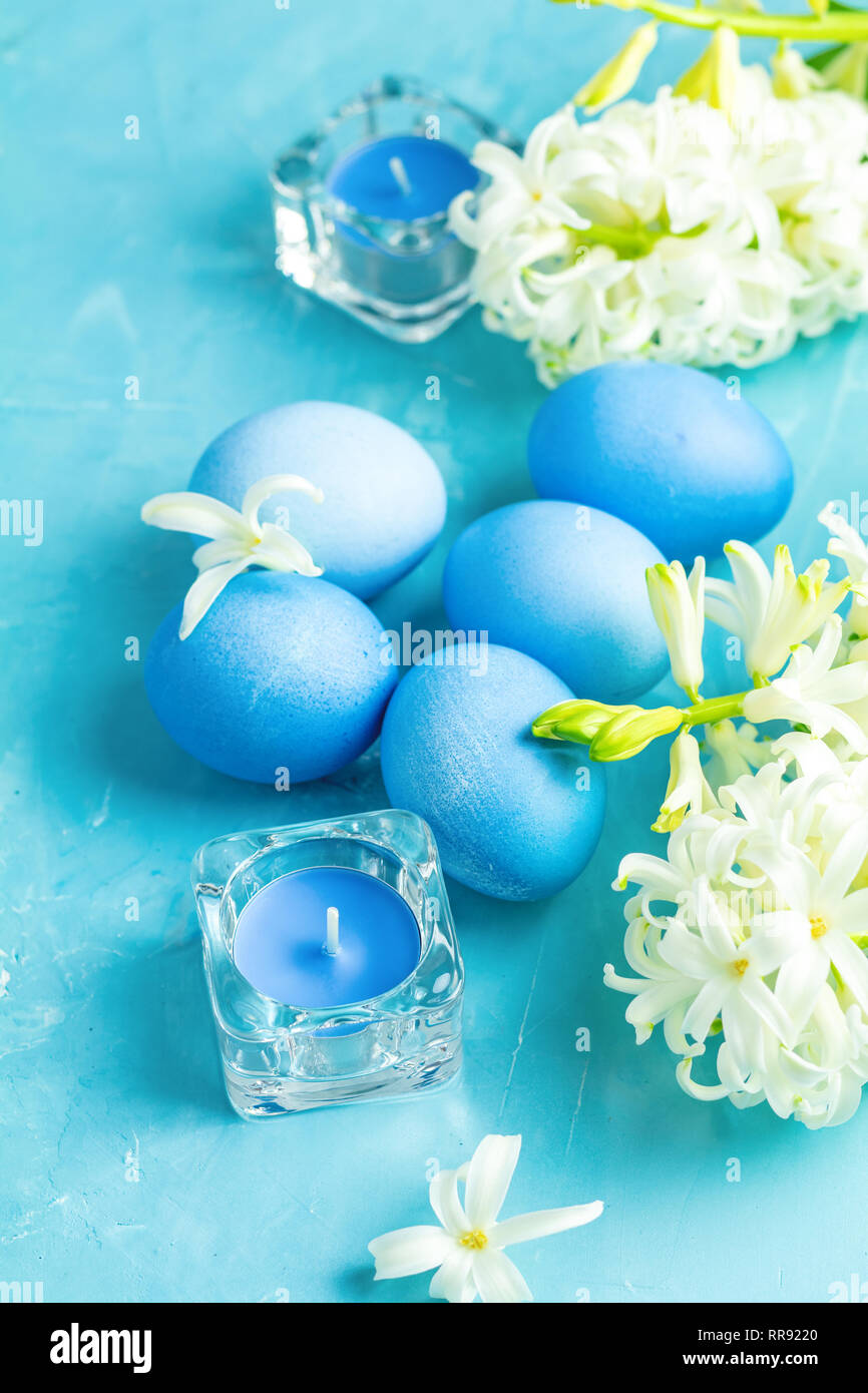 Blue easter eggs, candles and white hyacinth on blue concrete table ...