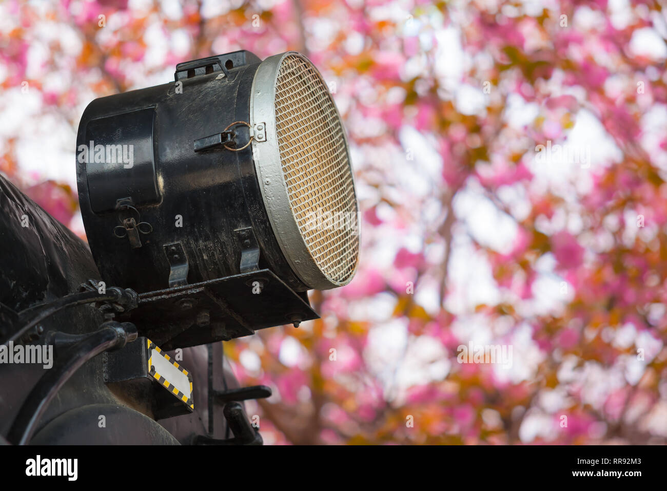 Detail of nostalgic steam locomotive headlight at pink cherry blossom ...