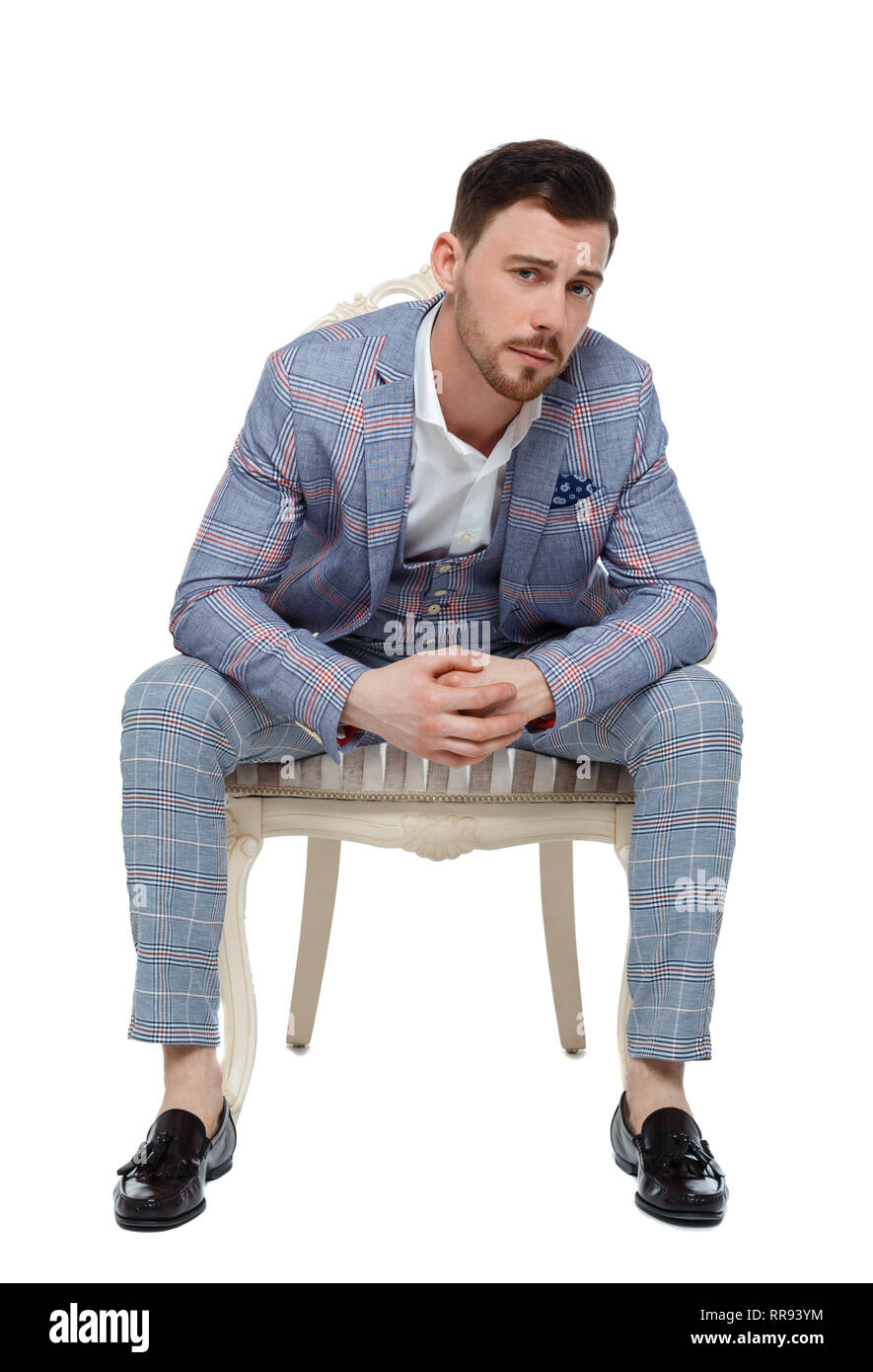 A man in a suit is sitting on an expensive chair. Front view of a guy ...