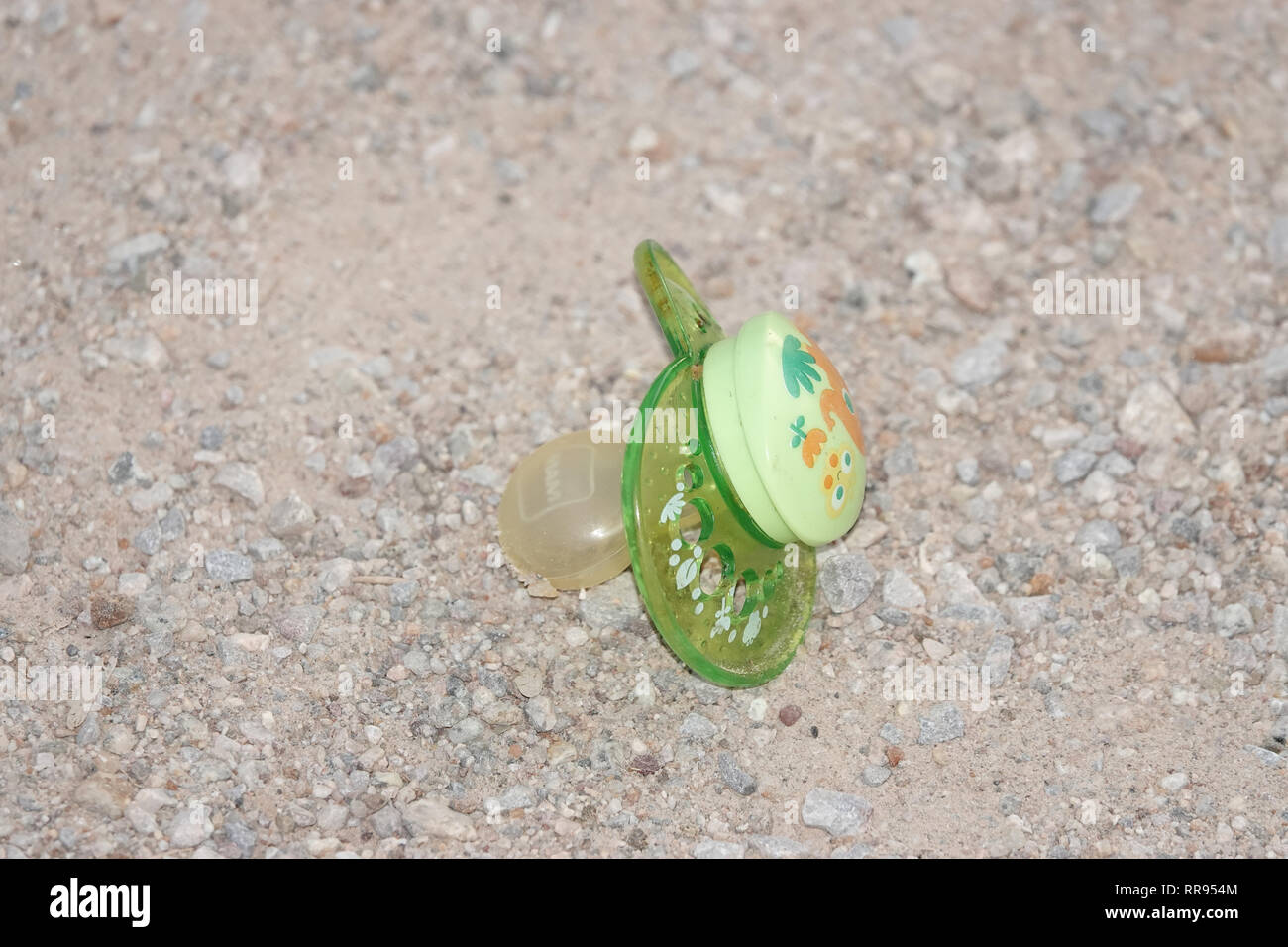 Lost green plastic pacifier lies on the ground Stock Photo - Alamy