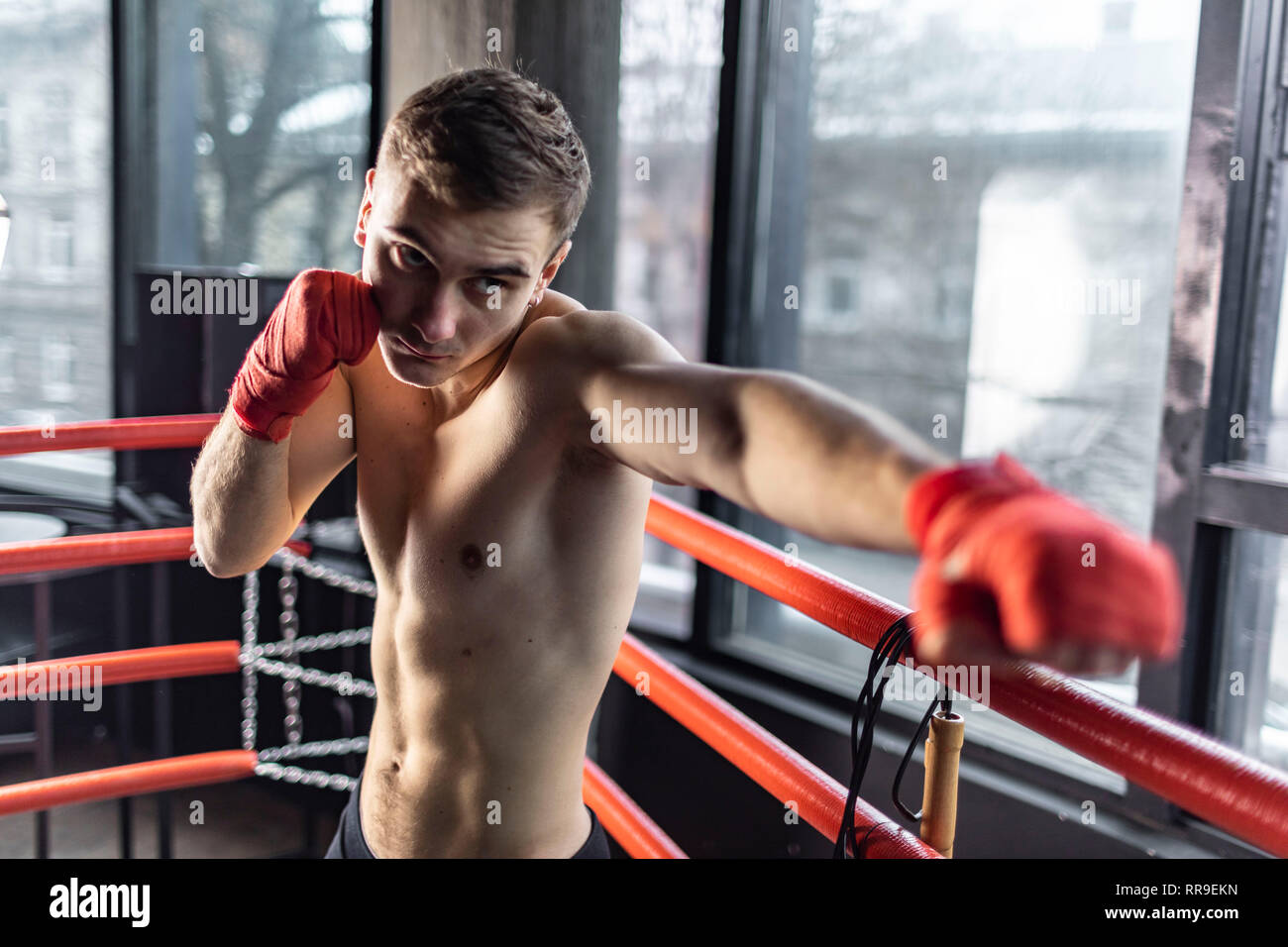 Punhing man with red bandages in the ring before wide window Stock ...
