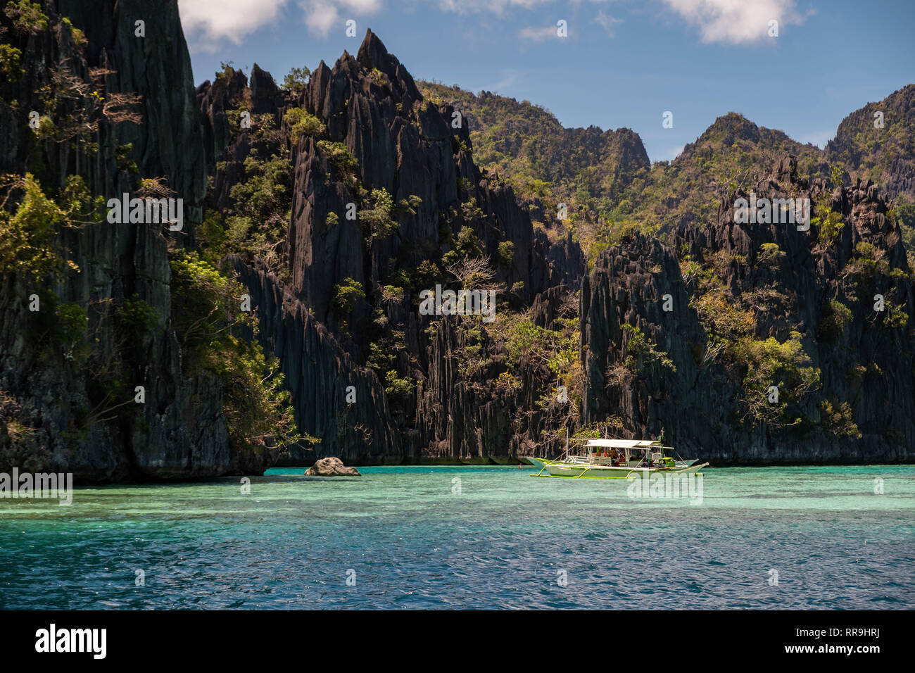 Boat floating on a lagoon surrounded by cliffs of limestone in Coron ...