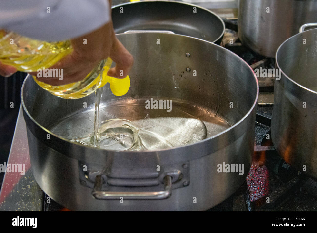 Chef pouring oil in frying pan, Chef cooking food in the kitchen Stock ...