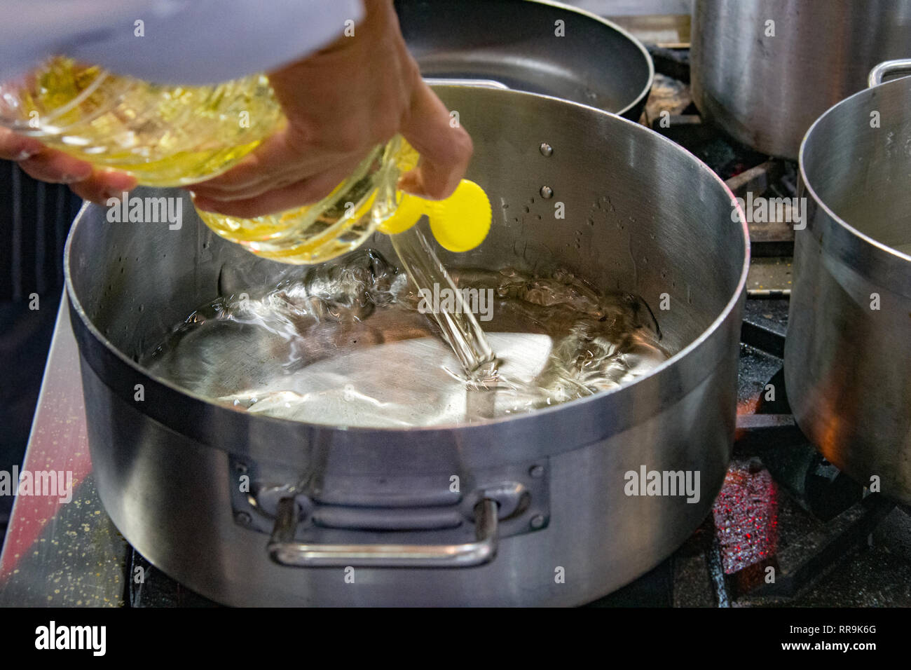 Chef pouring oil in frying pan, Chef cooking food in the kitchen Stock ...