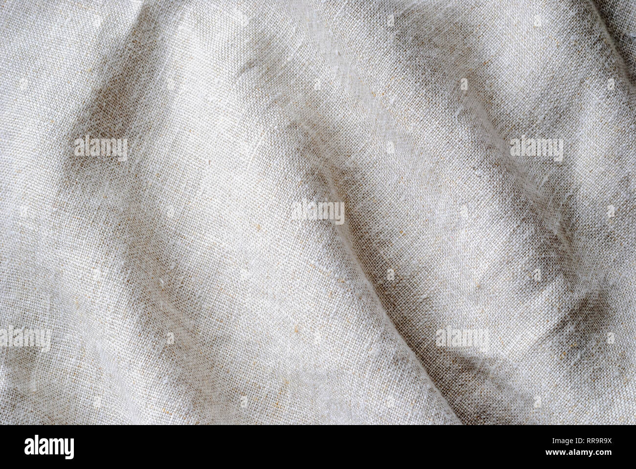 Soft folds of a natural woven linen fabric in close up detail in a full ...