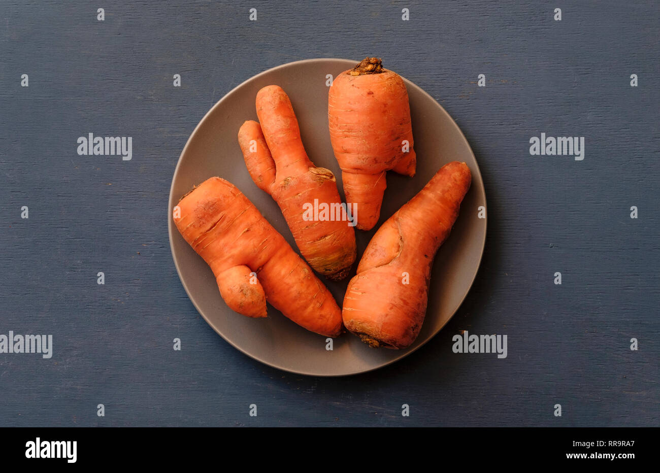 Plate with ugly carrots of different unusual imperfect shapes, viewed ...