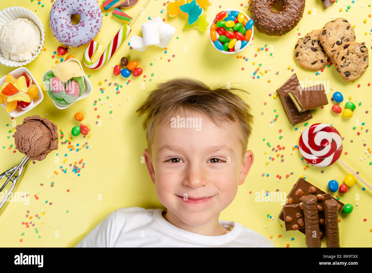 Boy with selection of sweets on bright background Stock Photo - Alamy