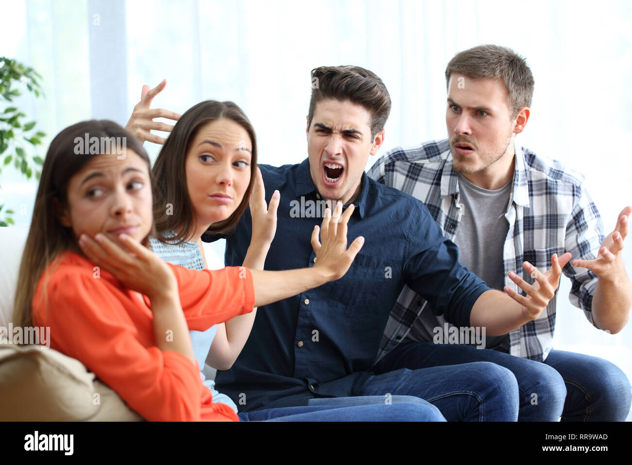 Two angry women ignoring men arguing at home Stock Photo - Alamy