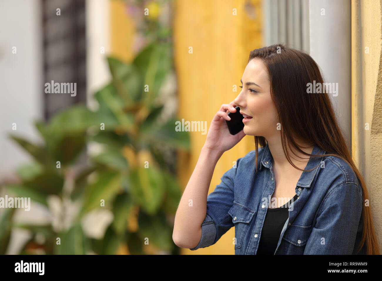Side view portrait of a woman having phone call standing in the street ...