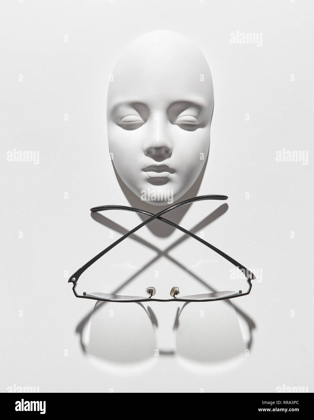 Gypsum face sculpture mask with stylish glasses, long crossing shadows on a white background ...