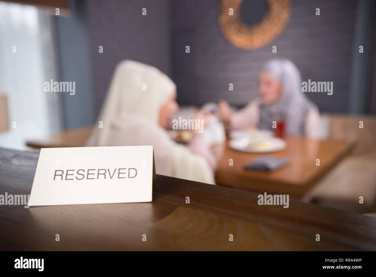 Reserved sign on the table. Two muslim woman sitting on the background ...