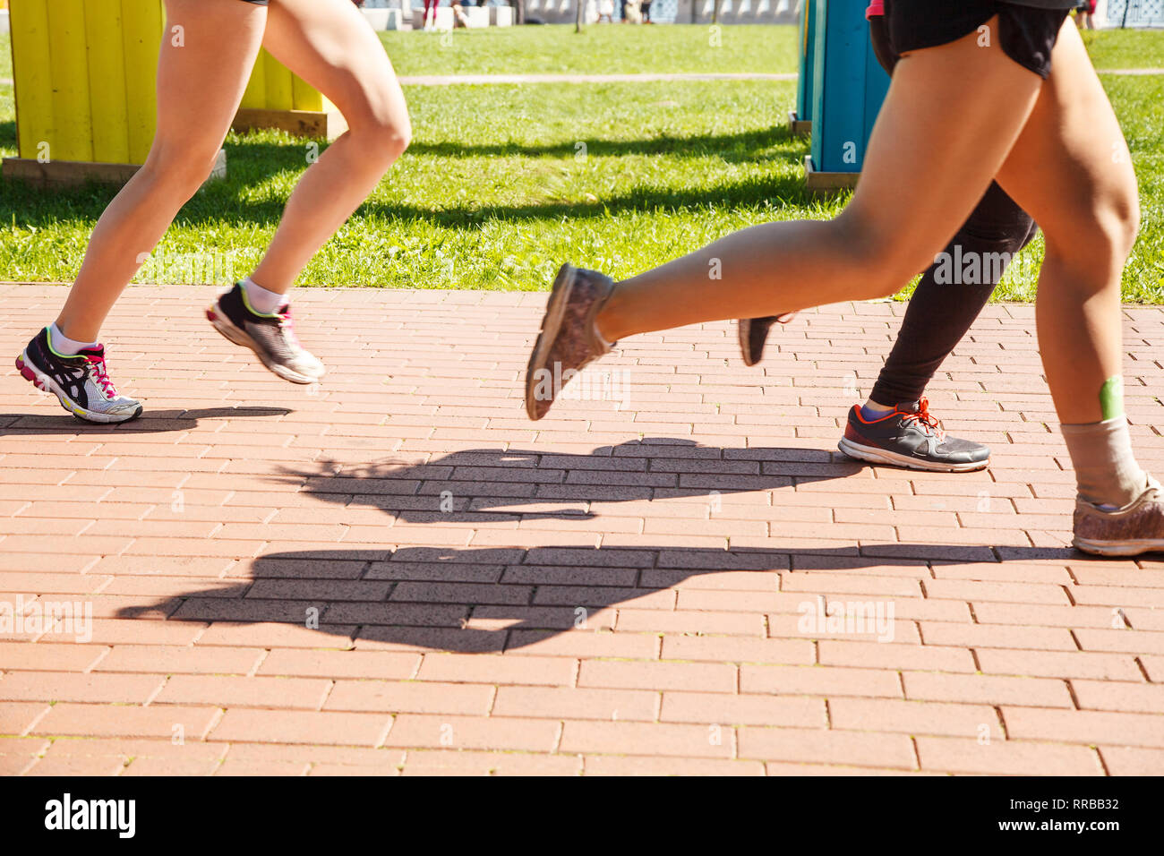 legs of girls running in a sports competition on sunny summer morning ...