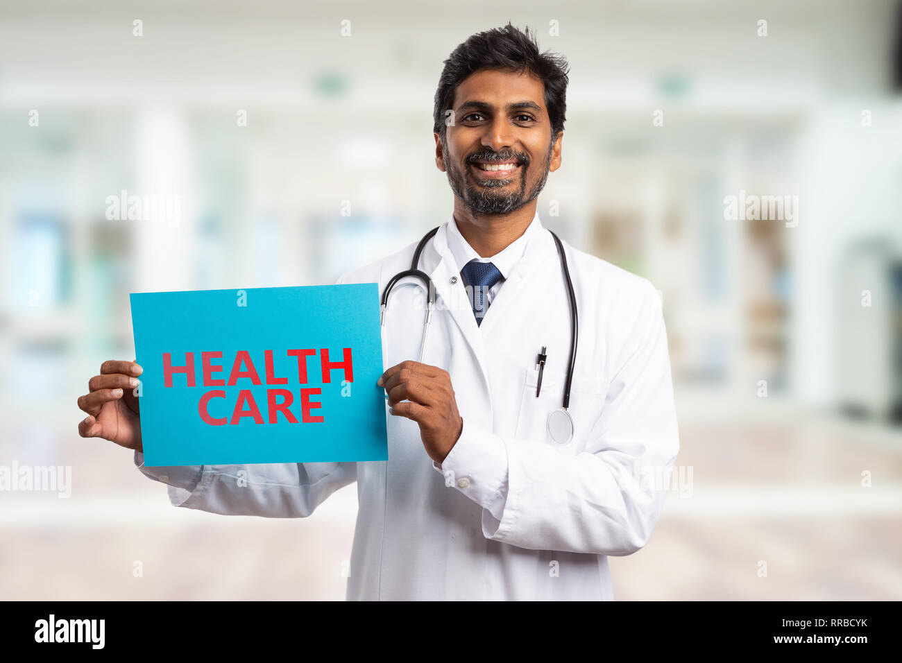 Indian male medic with friendly smile showing health care text on paper ...