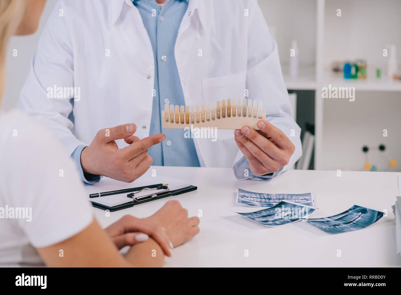 cropped view of dentist in white coat pointing with finger at teeth ...
